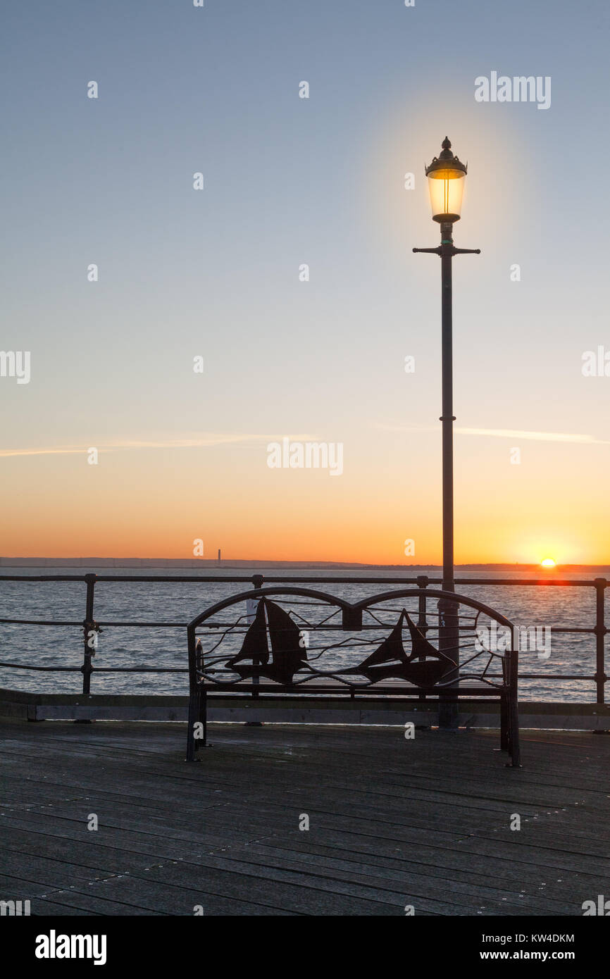 Iron Bench and Lamp-post at the end of the pier at sunset Stock Photo ...