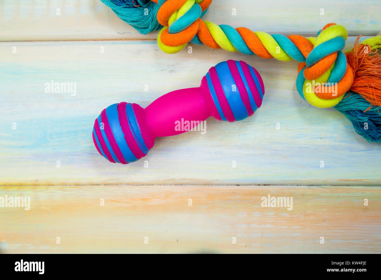 Rubber and textile pet toys- a bright pink rubber bone and colorful ...