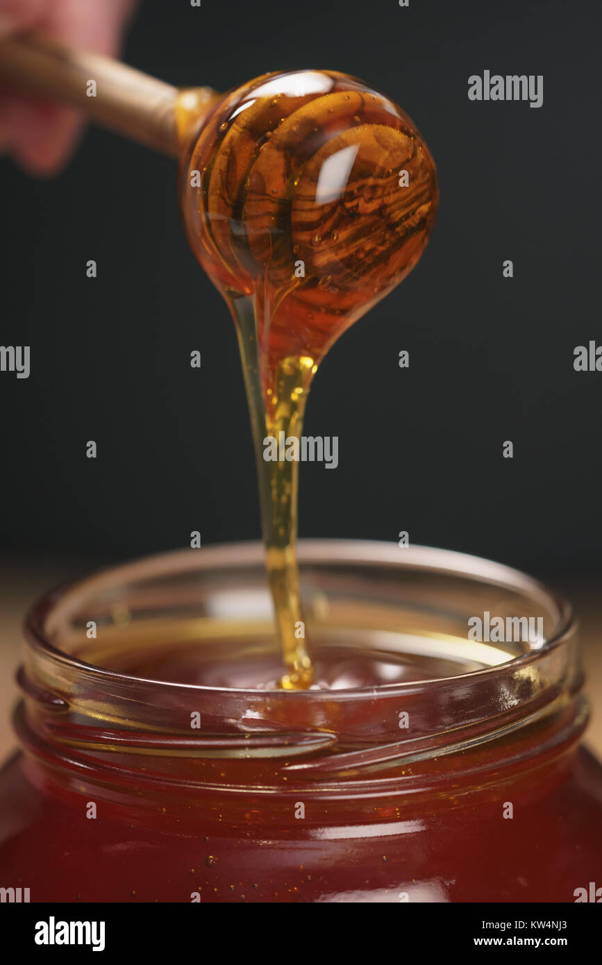 pouring organic honey from dipper into glass jar, shallow focus Stock ...