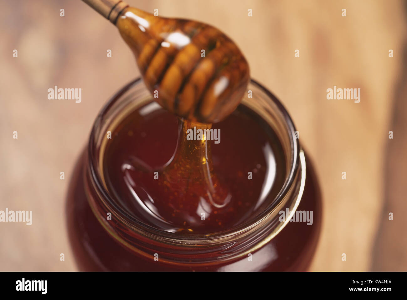 pouring organic honey from dipper into glass jar, shallow focus Stock ...