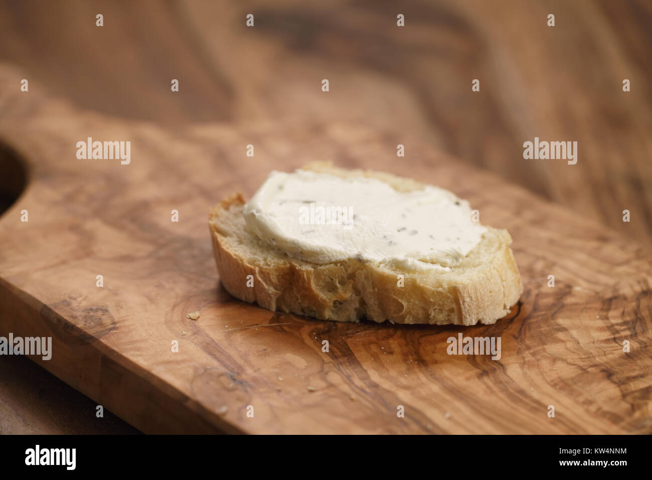crunchy baguette slice with cream cheese on olive board, closeup Stock ...