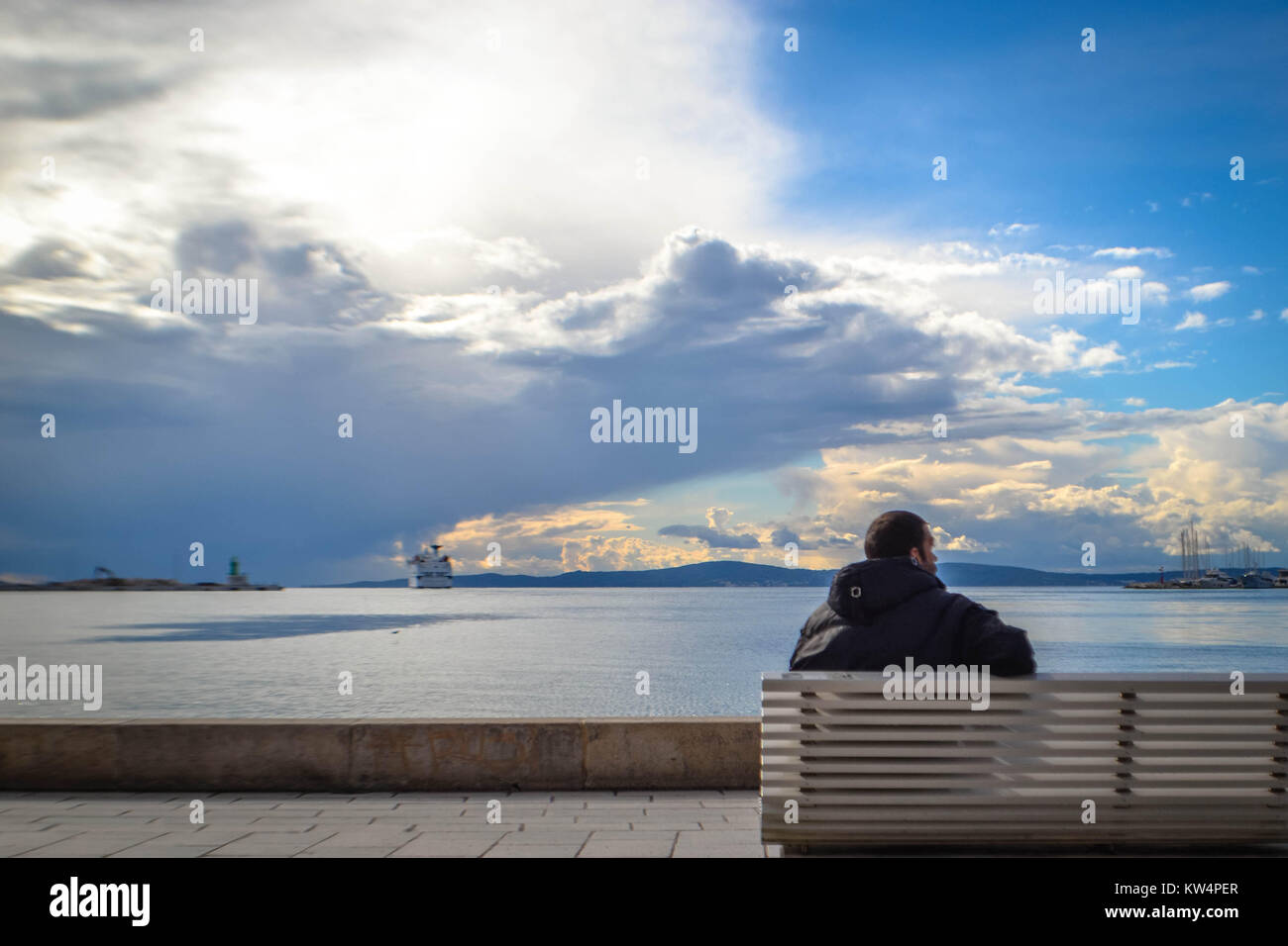 Man sitting at the wooden bench and looking at panoramic sea view Stock ...