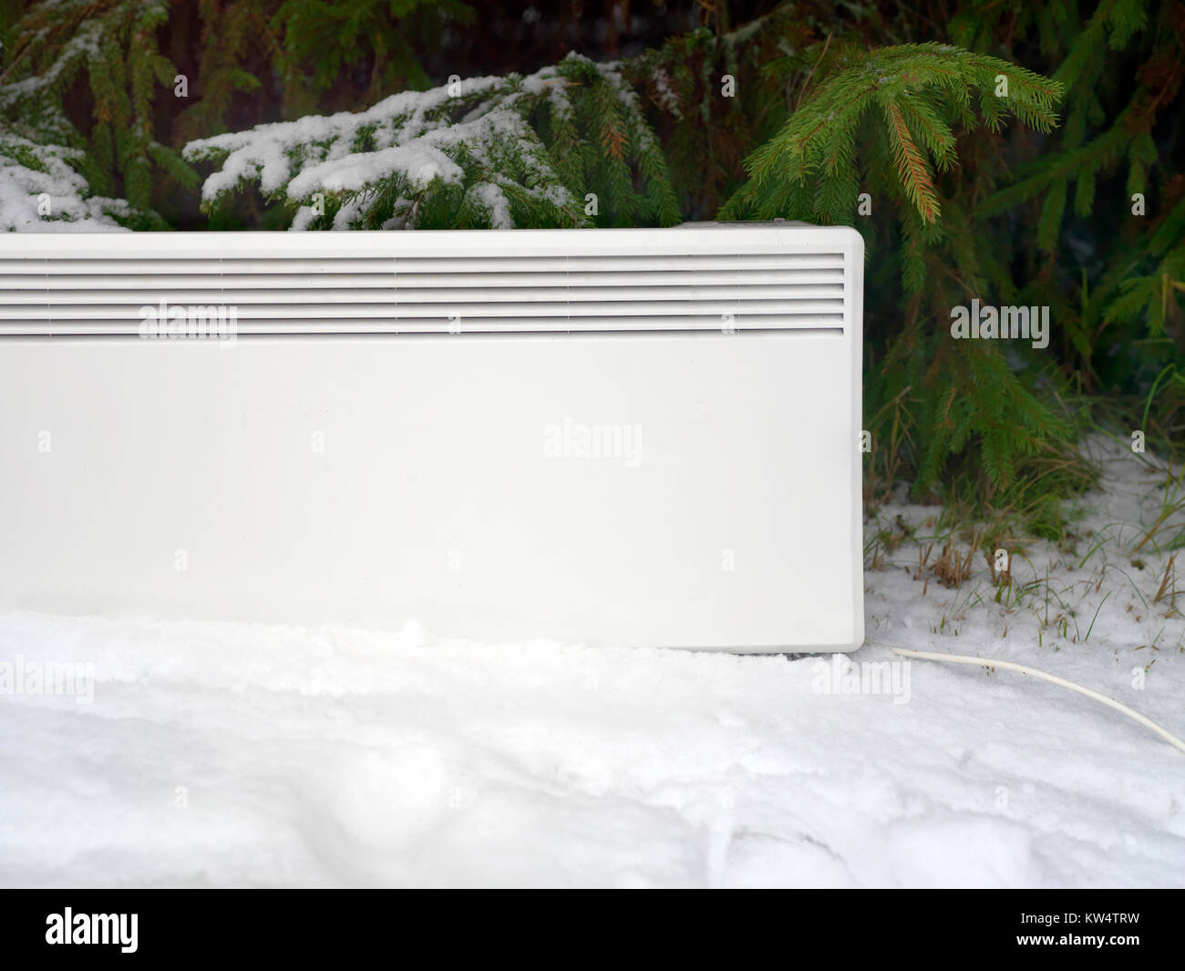 Electric heater placed on the snow under evergreen tree, outdoor ...