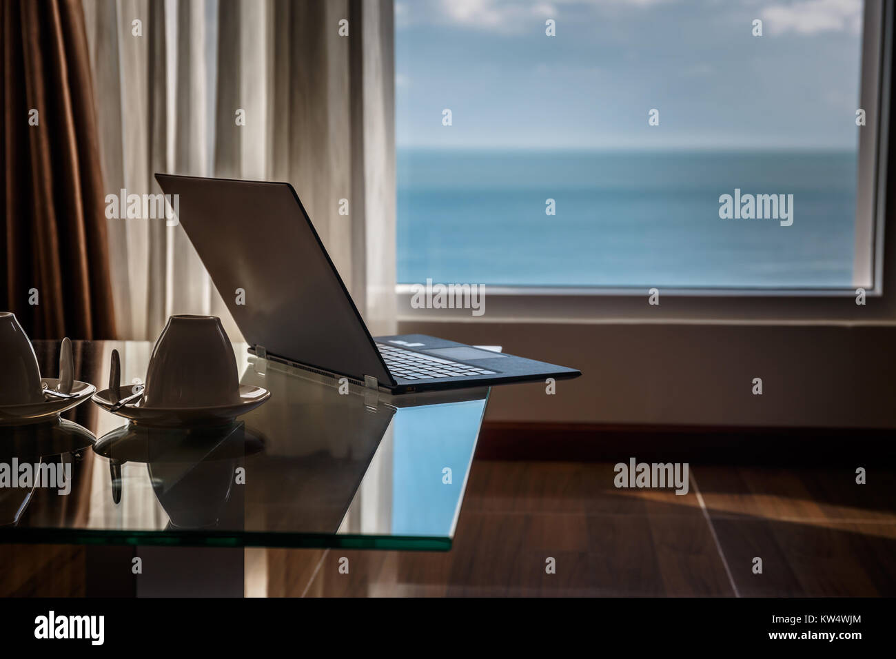 Thin laptop on glass table Stock Photo - Alamy