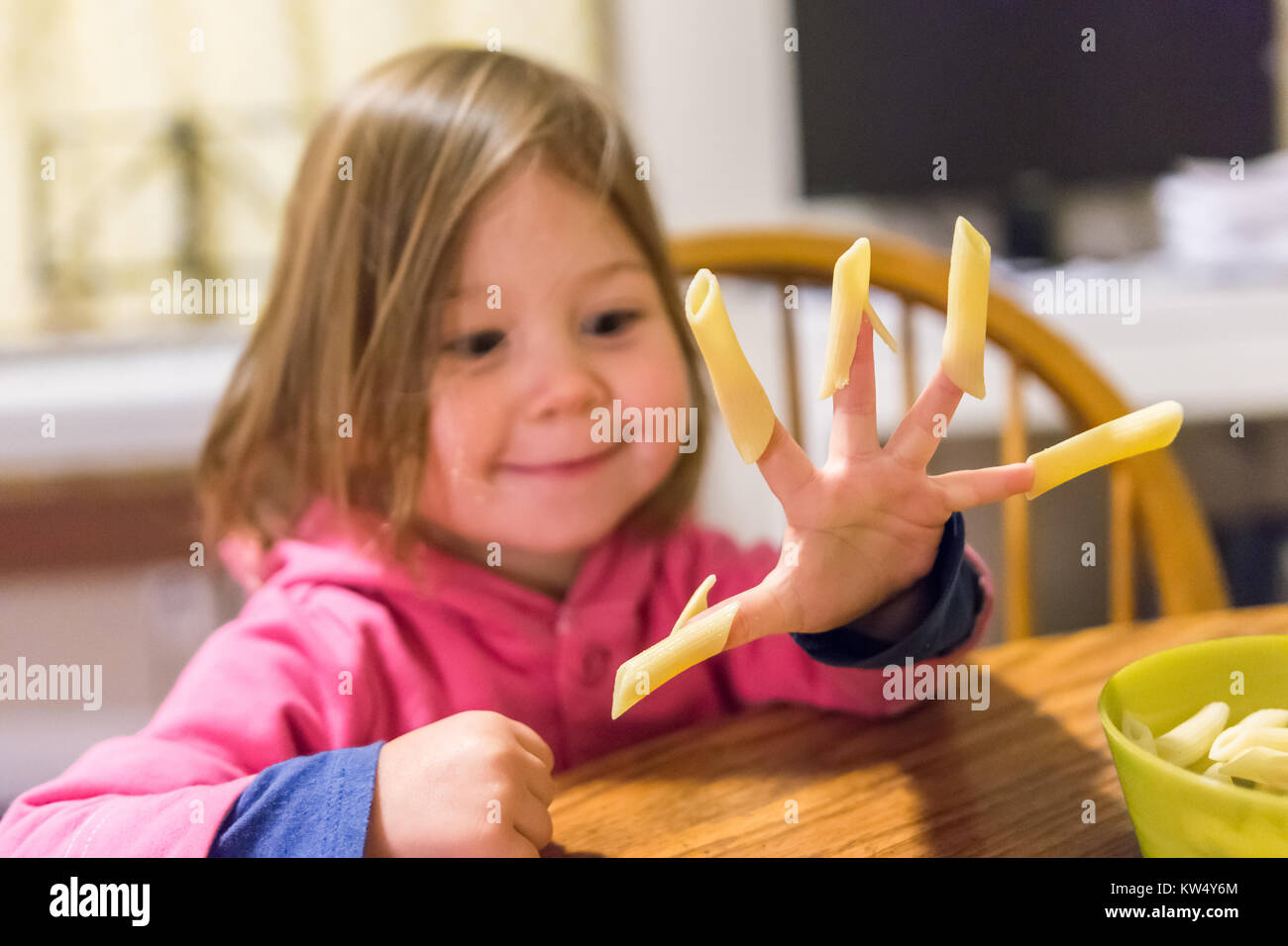 Little girl with penne pasta on fingers Stock Photo - Alamy