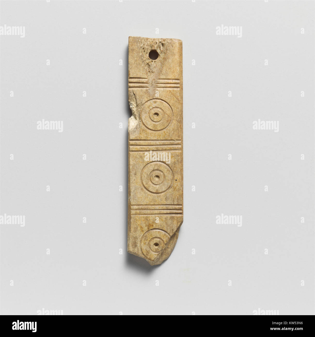 A bone plaque featuring a hole at one end, an ancient artifact ...