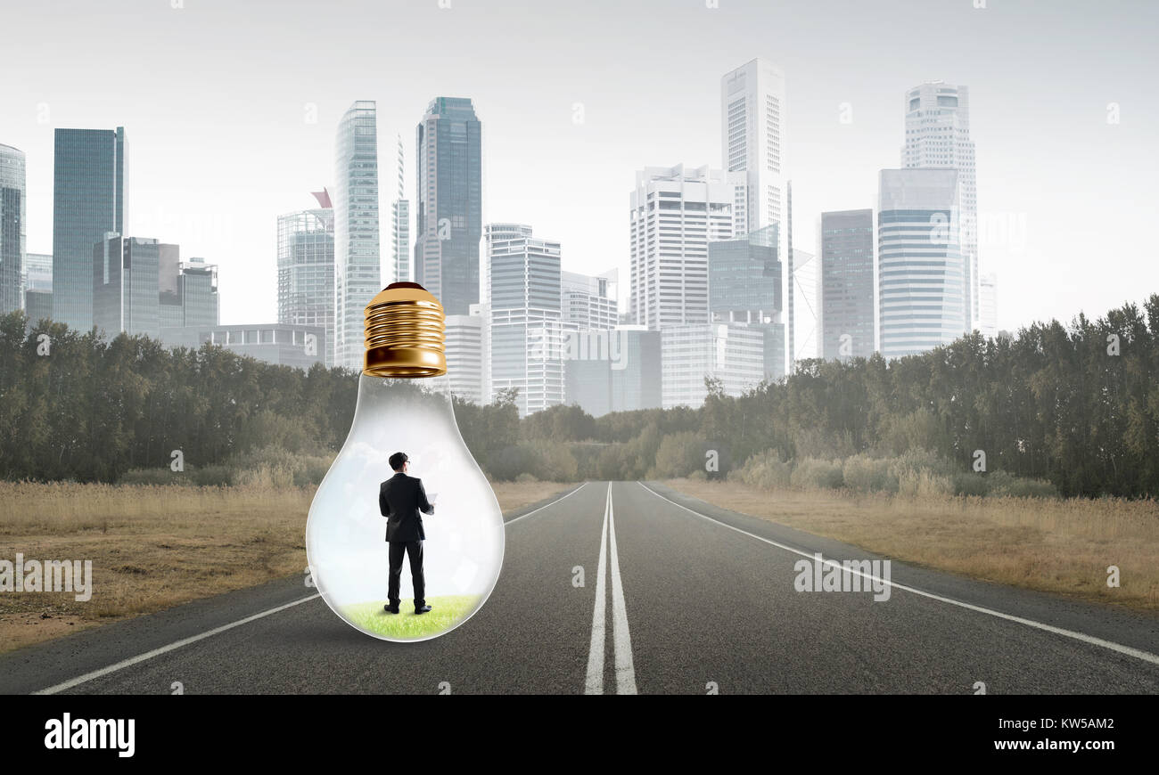 Young businessman trapped inside of light bulb on asphalt road Stock ...