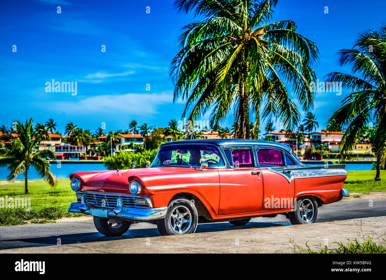 American red Ford classic car parked under blue sky near the beach in ...