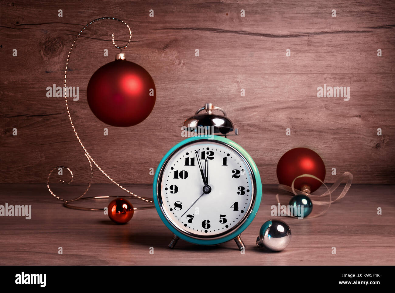 Vintage alarm clock showing five to twelve with Christmas baubles on ...