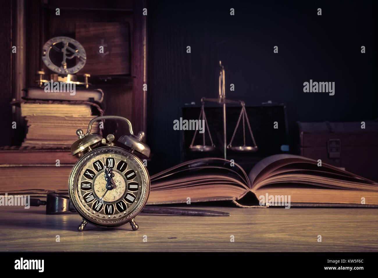 Vintage alarm clock showing five to twelve on the wooden table in study ...