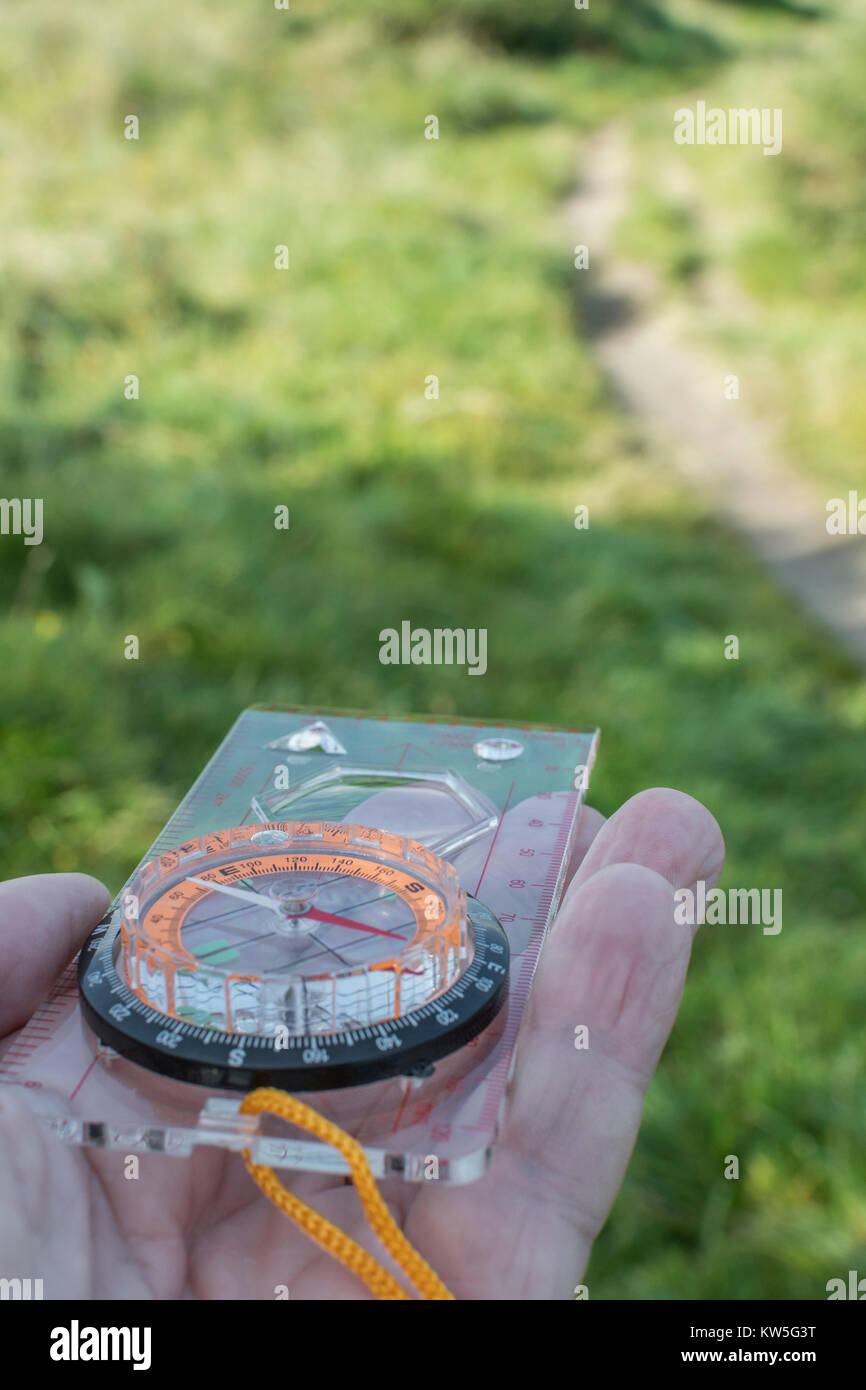 Orienteering compass in hand pointing west. For business 'direction ...