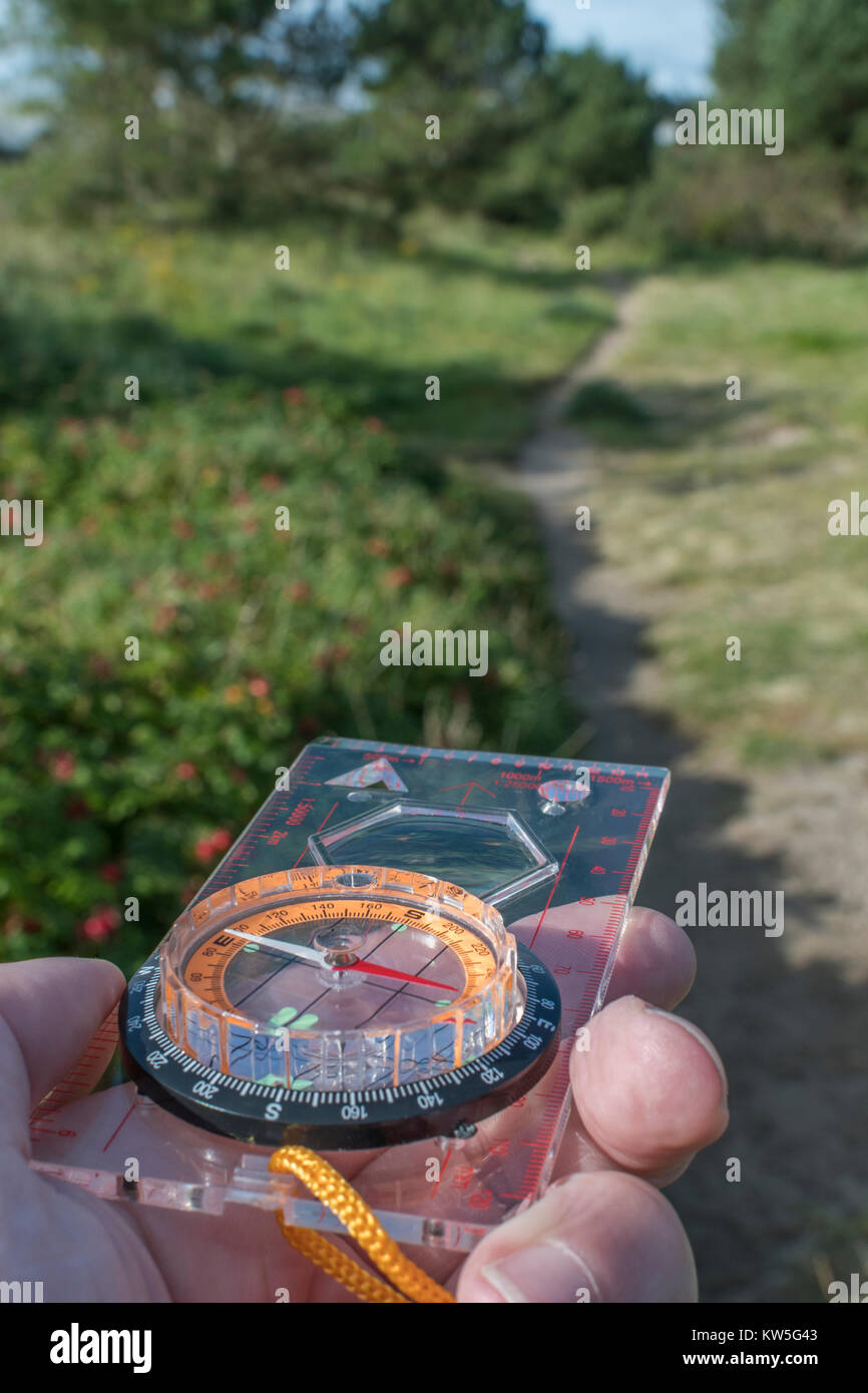 Orienteering compass in hand pointing west. For business 'direction ...