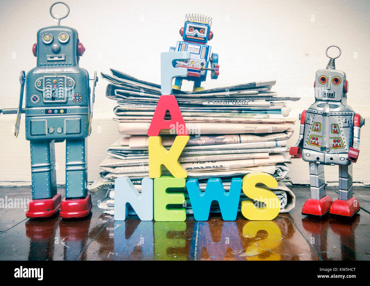 three retro robots a pile of old newspaper with the word FAKE NEWS on a ...