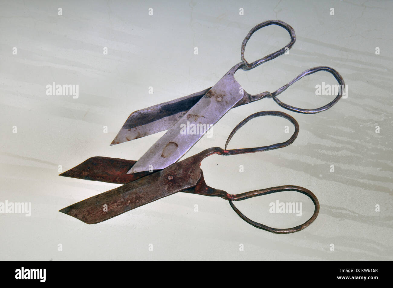 Two old vintage metal scissors laconically shaped on a light background ...