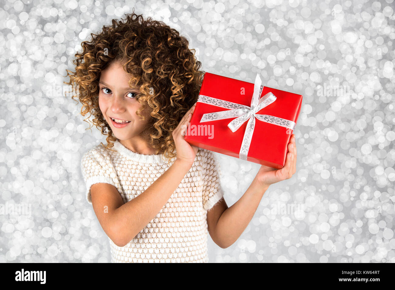 Smiling girl holds gift bow on a sparkling white background Stock Photo ...