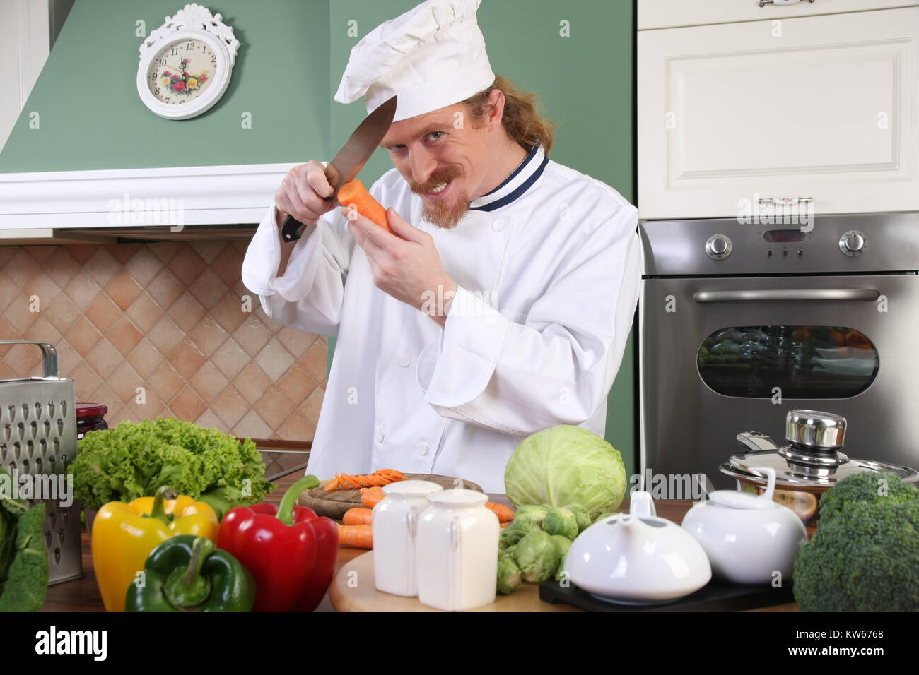 Funny young chef with carrot, preparing lunch in kitchen Stock Photo ...