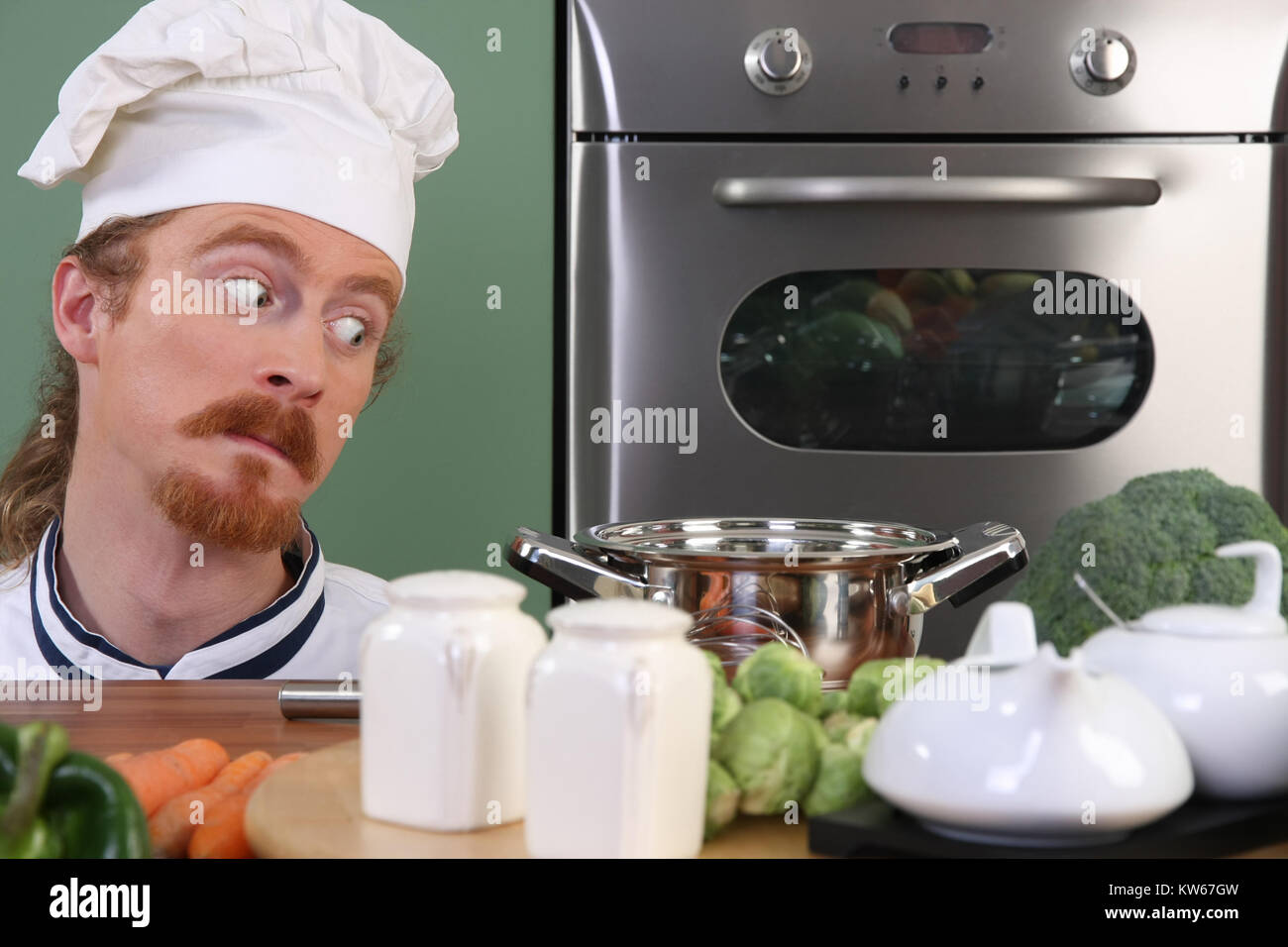 Funny young chef strange looking at pot Stock Photo - Alamy