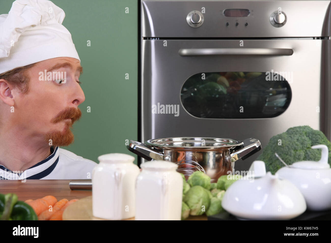 Funny young chef strange looking at pot Stock Photo - Alamy