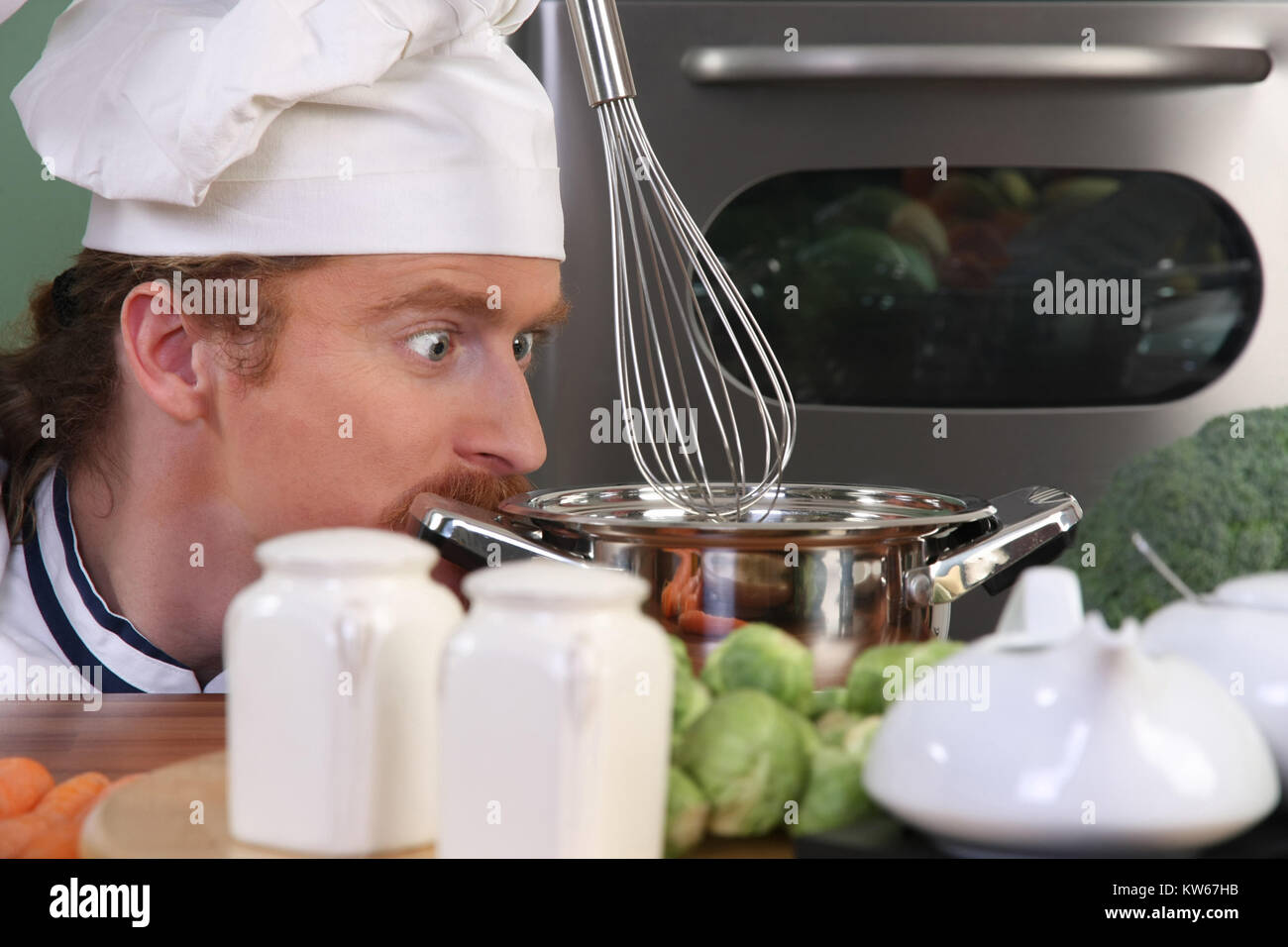 Funny young chef strange looking at pot Stock Photo - Alamy