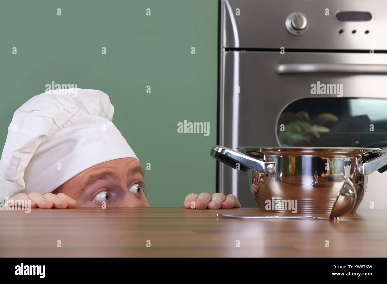 Funny young chef strange looking at pot Stock Photo - Alamy