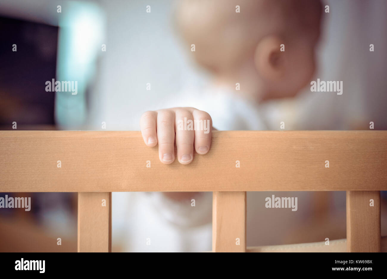Child's hand on a crib closeup. Baby is standing in his crib and ...