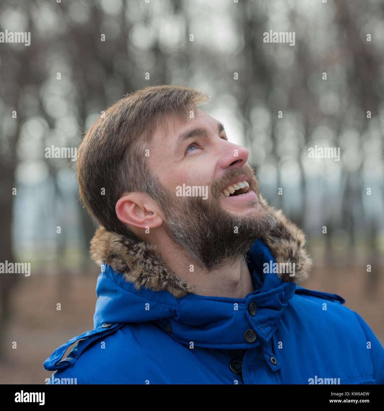 bearded man looks to the side and up in the city park. Bearded man ...