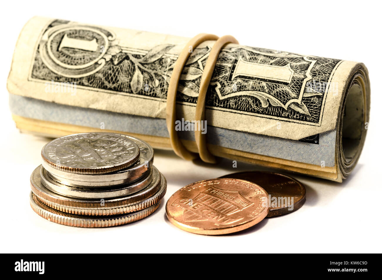 close up of dollar bill roll and coin in pile over a white background ...