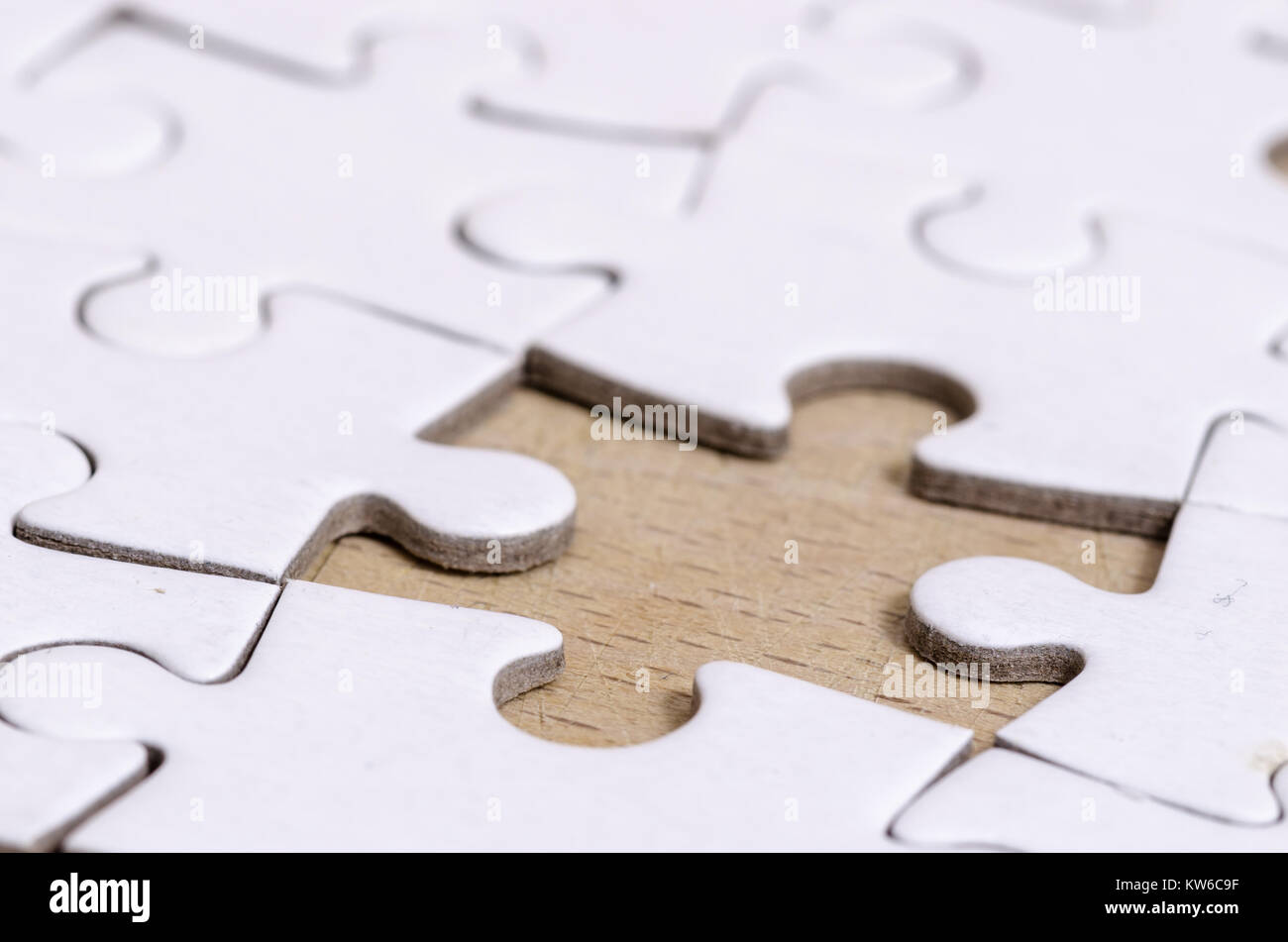 white jigsaw/puzzle with one gap, over wooden table background, symbol ...