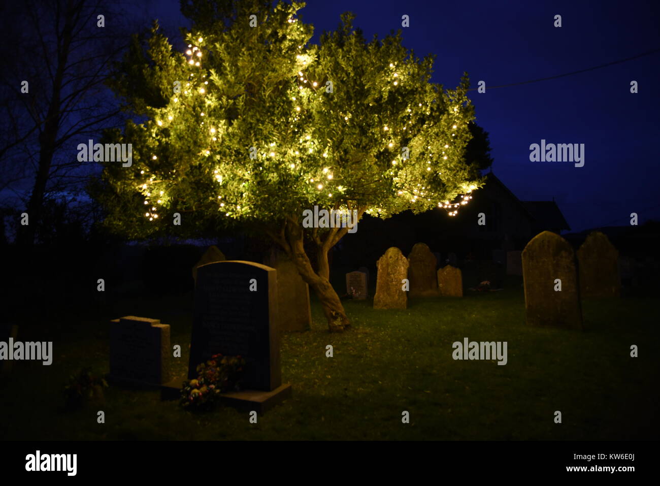 Gravestones illuminated at night in a village cemetery, Devon, England ...