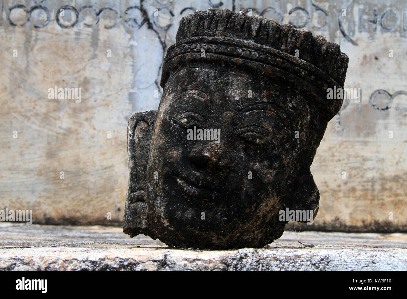 Head of stone Buddha near wall of temple, Myanmar Stock Photo - Alamy