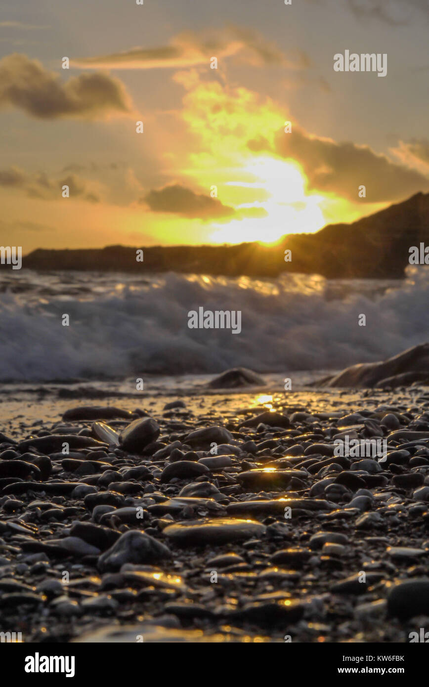 Sunset on pebble beach Stock Photo - Alamy