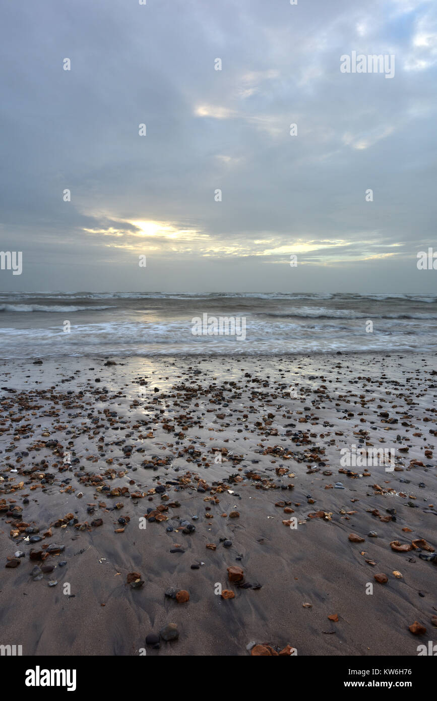 a deserted stony beach at sunset with a moody and atmospheric beach ...