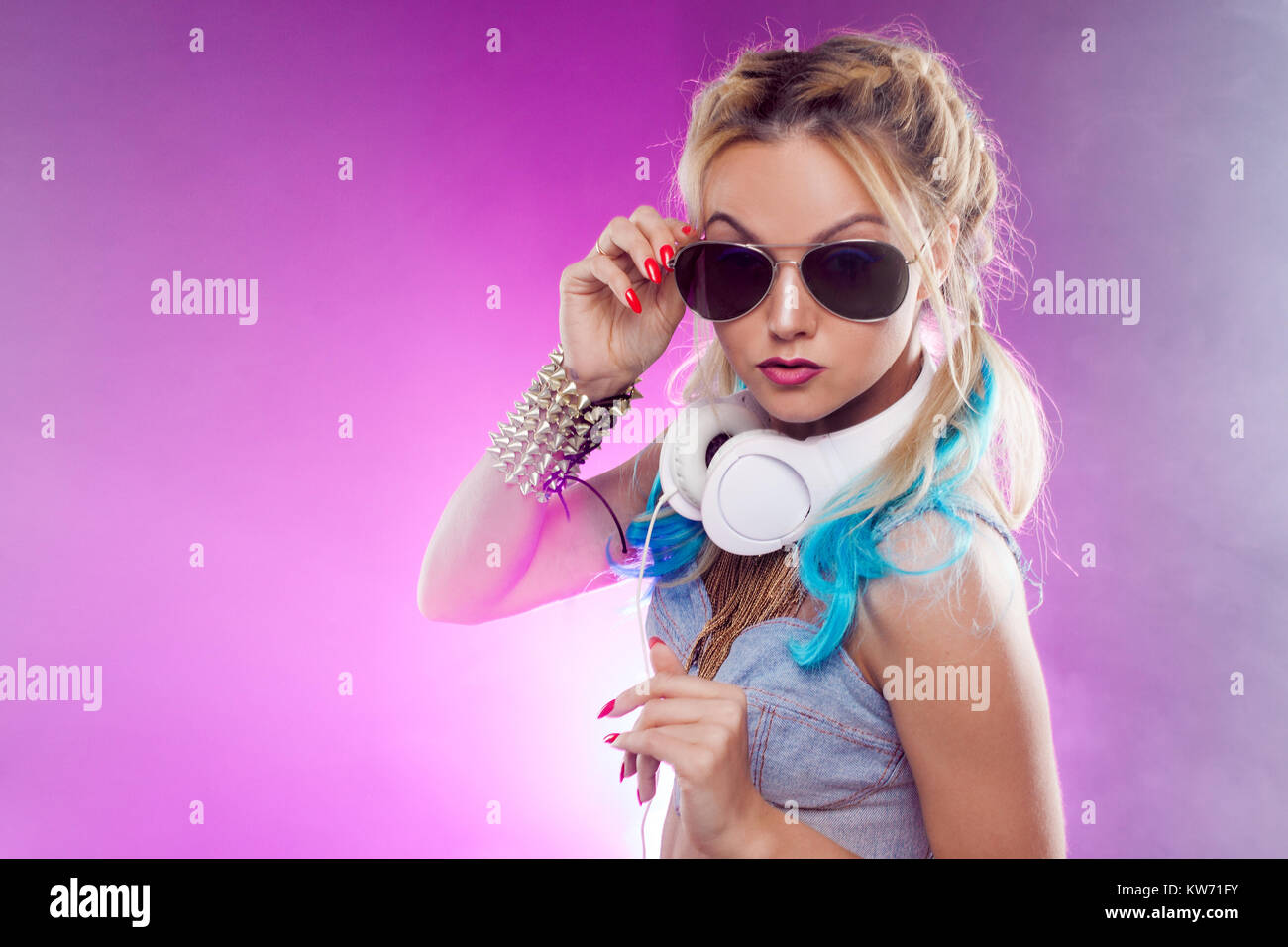 Young fashionable girl in disco style. Listening to music and enjoying ...