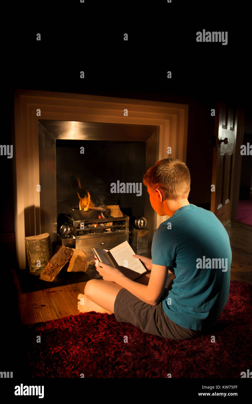 Teenage boy reading beside the fire. Hygge Stock Photo - Alamy
