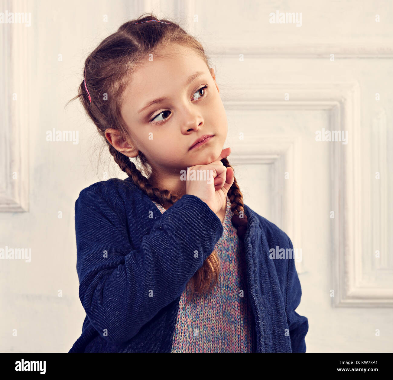 Thinking kid girl in fashion blouse and jeans jacket with serious ...