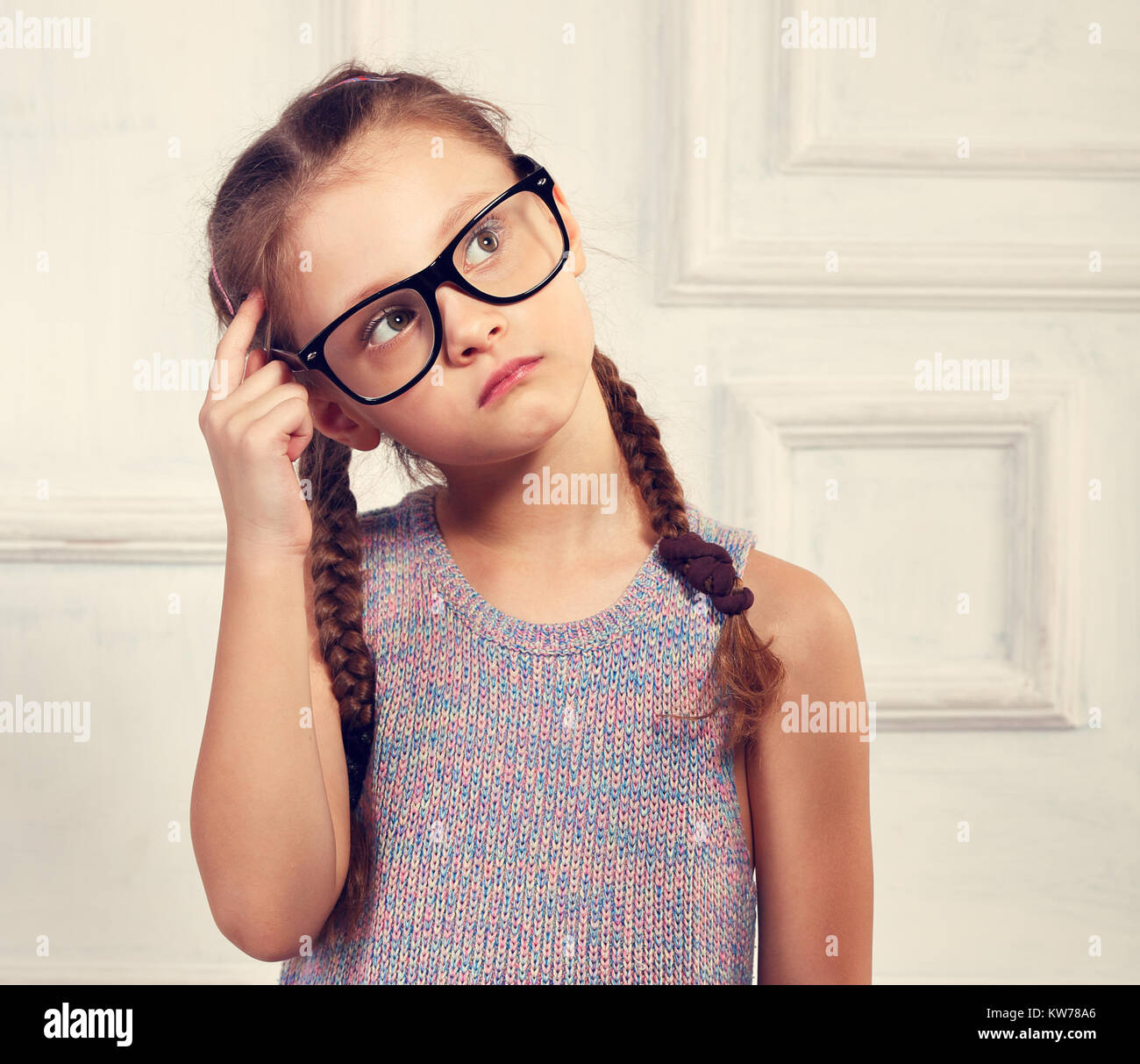 Happy thinking kid girl in fashion glasses and blouse with serious ...