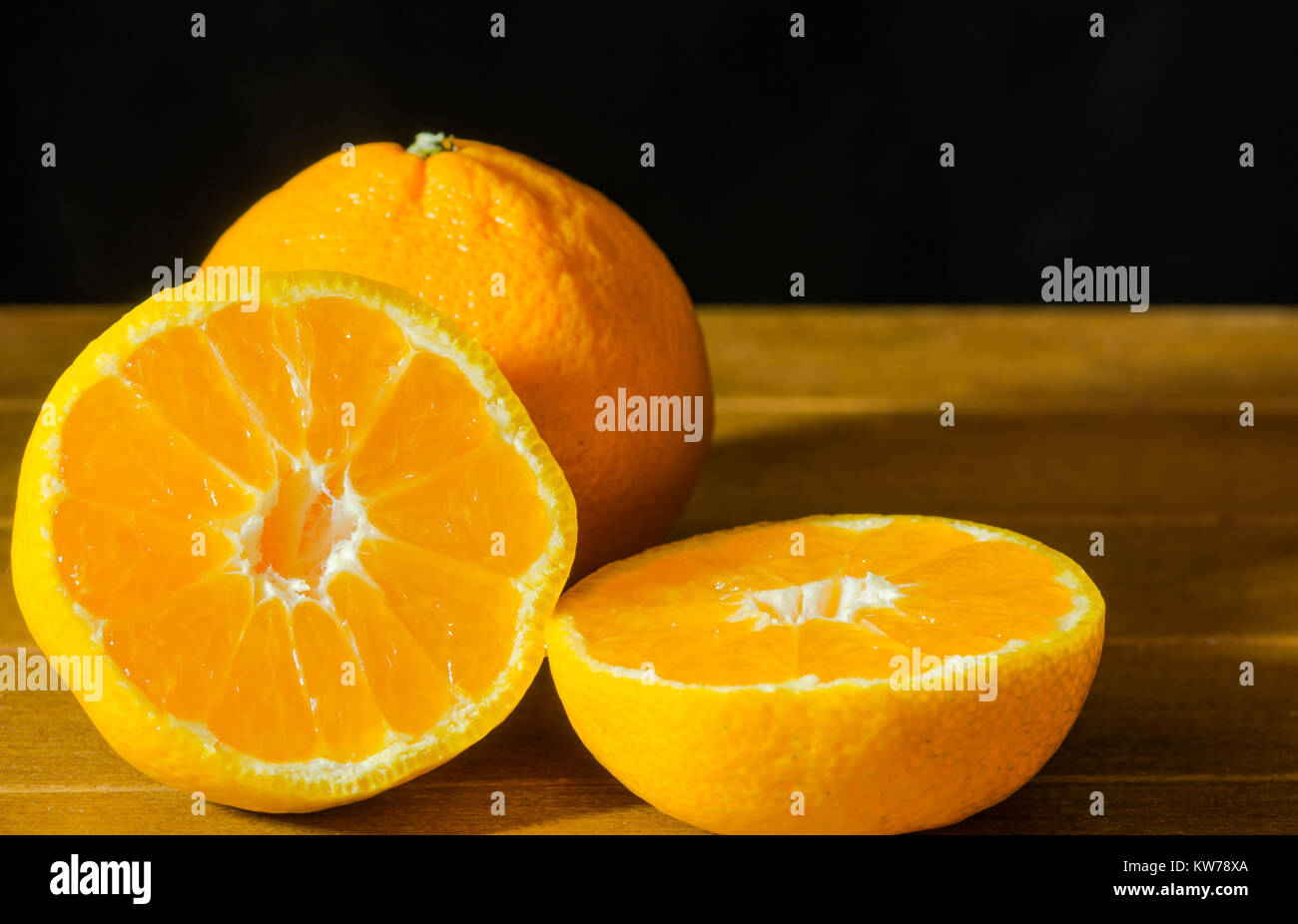 Ripe Mandarin fruit peeled open and place on old rustic look timber ...