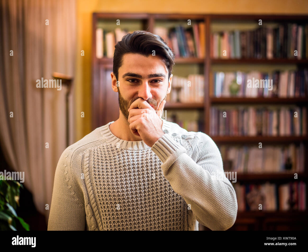 Handsome young man covering his mouth with hand, not laughing or in ...