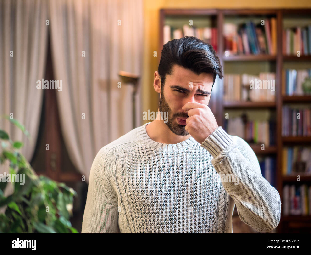 Portrait of caucasian young man closing nose with his hand because of ...