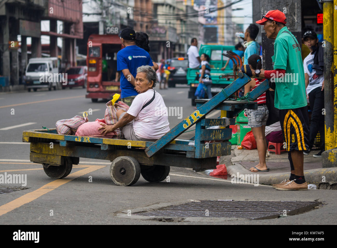 A man pushing a wooden pushcart with a woman sitting on top,downtown ...
