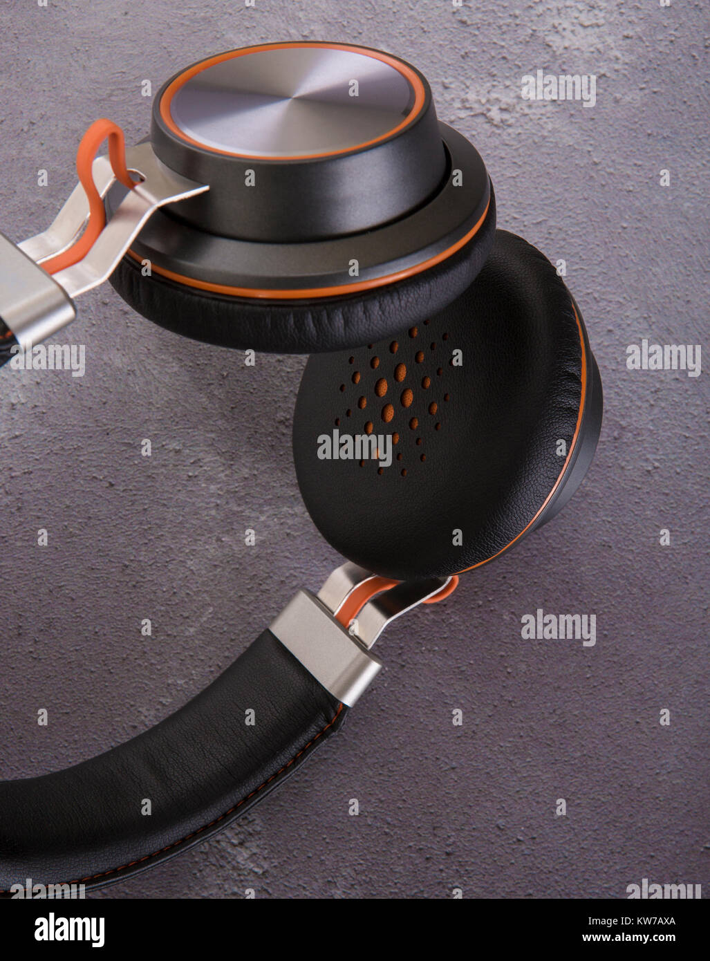 Pair of modern black and orange bluetooth headphones on a grey rustict ...