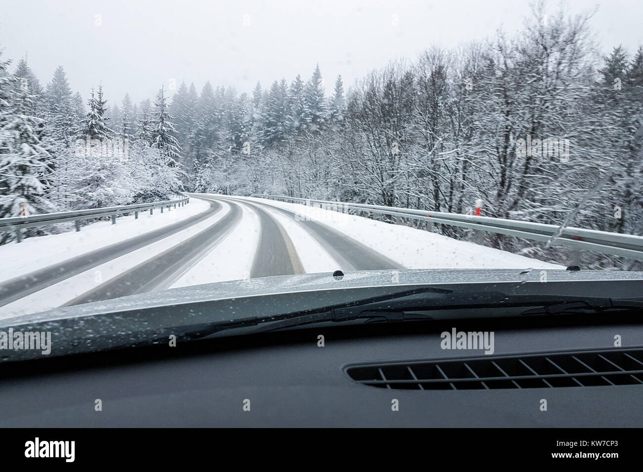 Driving a car in bad weather - a front window view of a snowy road ...