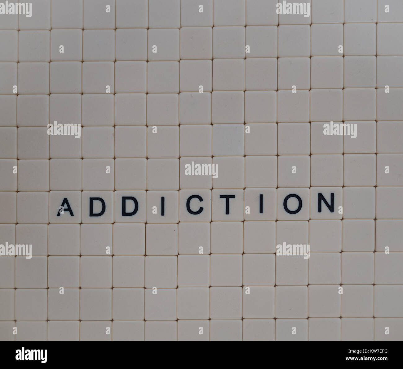 Addiction spelled in black capital letters on beige tiles with a ...