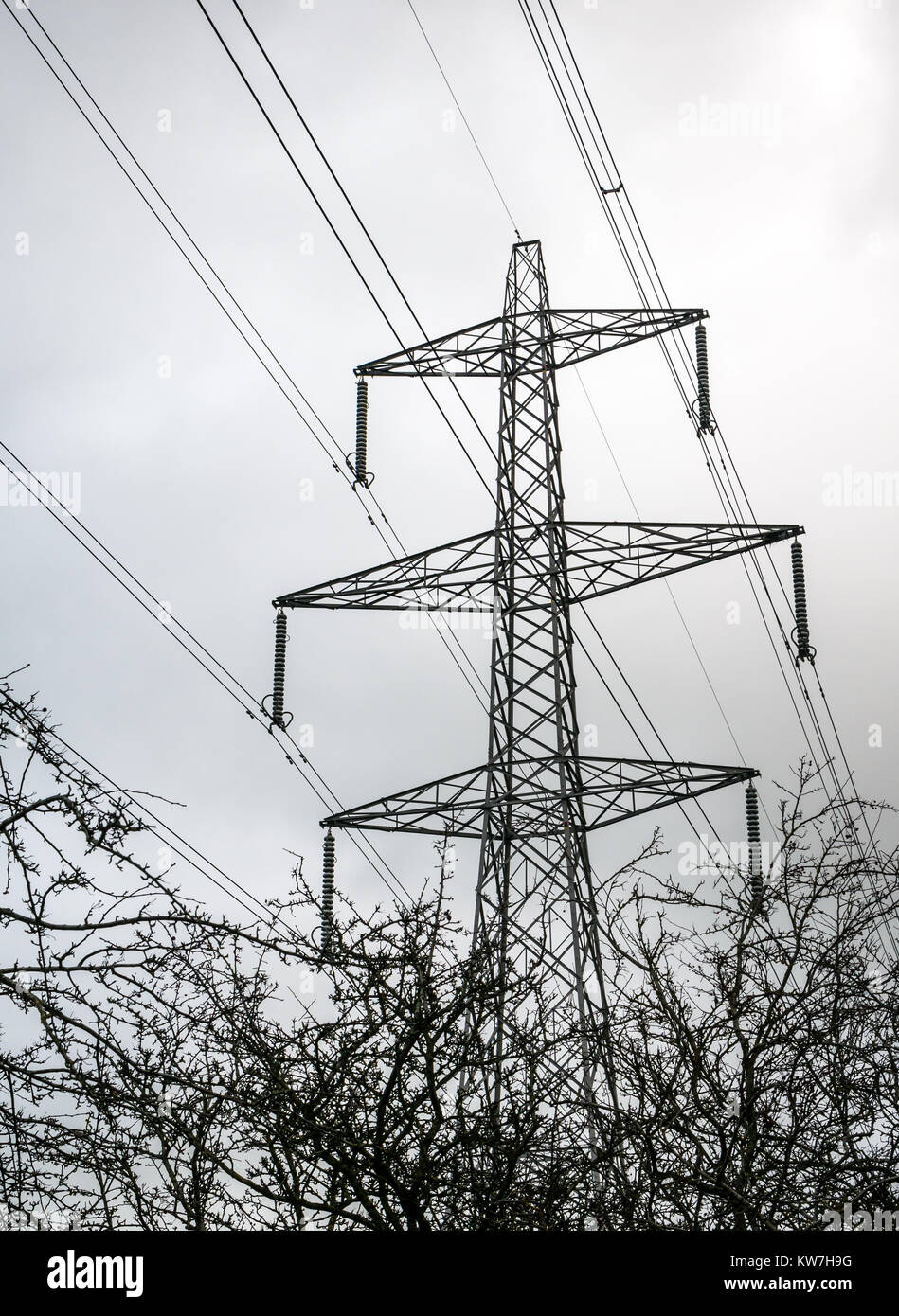 High lattice electricity pylon with coils and cables against cloudy sky ...