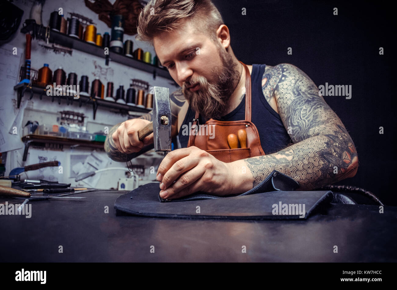 Close up of a shoemaker man working with leather using crafting tools ...