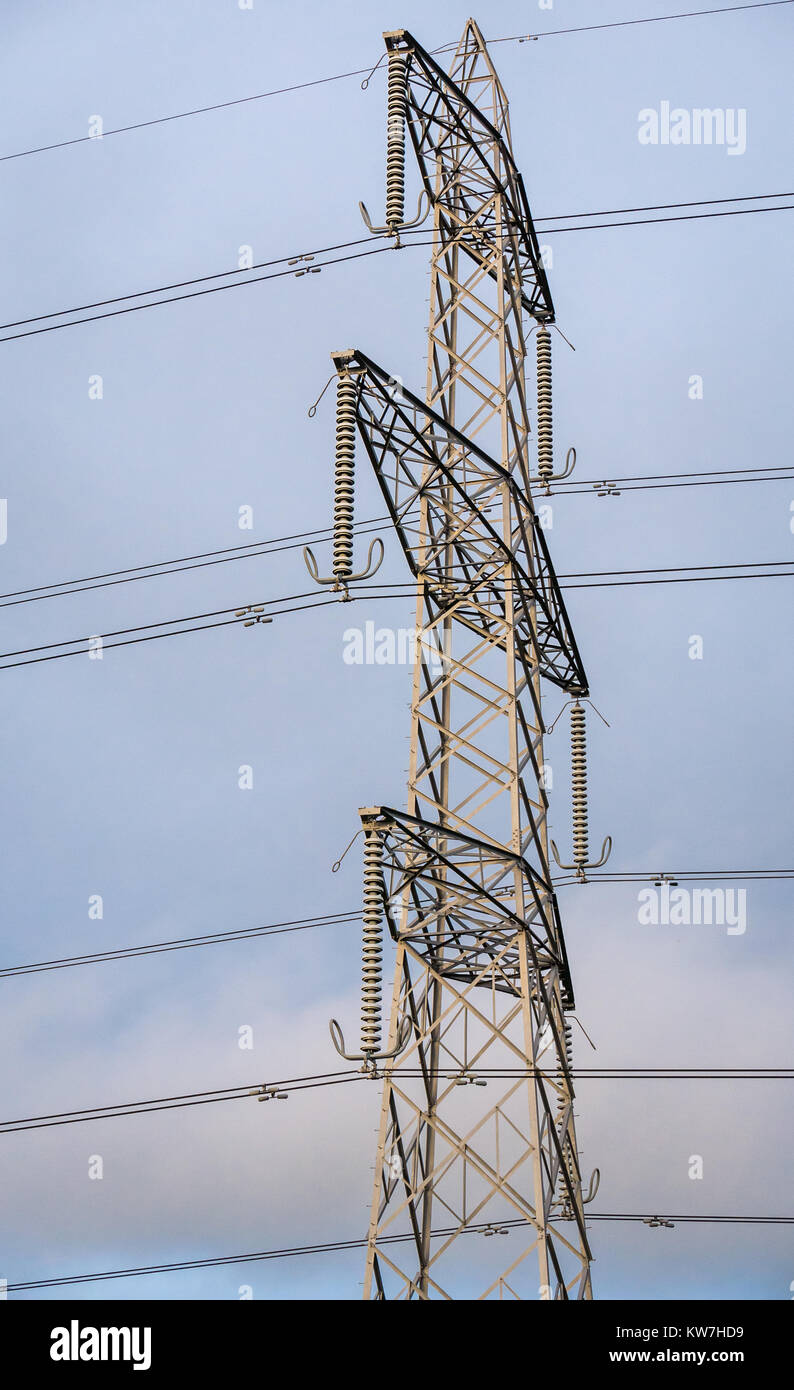 High lattice electricity pylon with coils and cables against cloudy sky ...