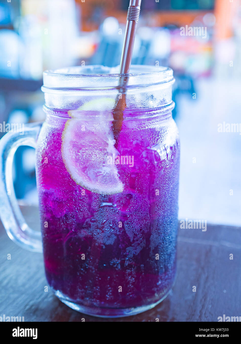 ice purple butterfly pea flower tea with a piece of lime in clear glass ...