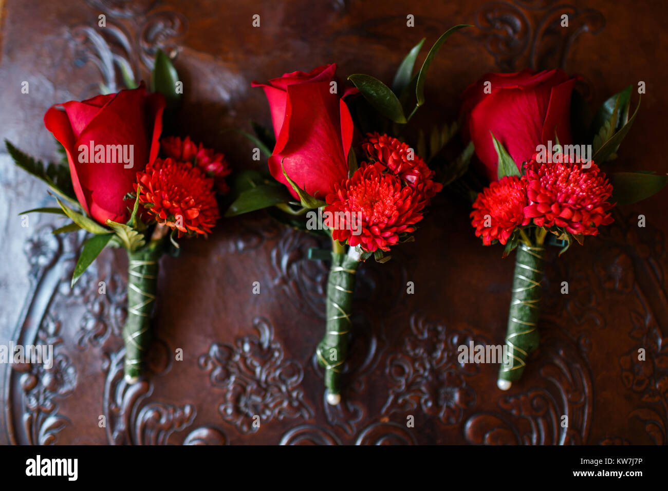 Wedding set of three boutonnieres of red roses on a leather chair Stock ...