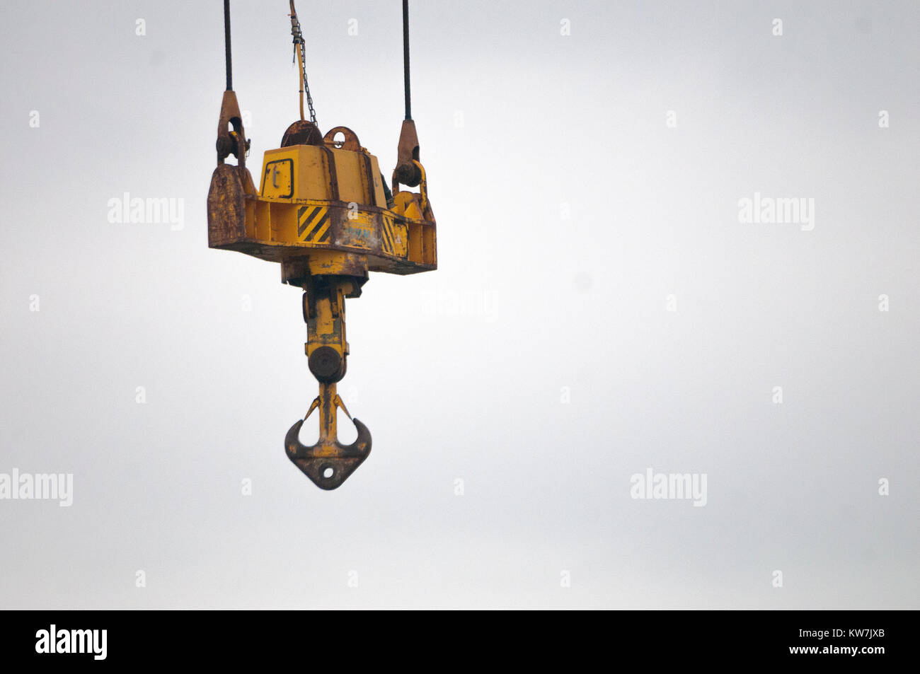 A big yellow crane hook suspended in the sky Stock Photo - Alamy