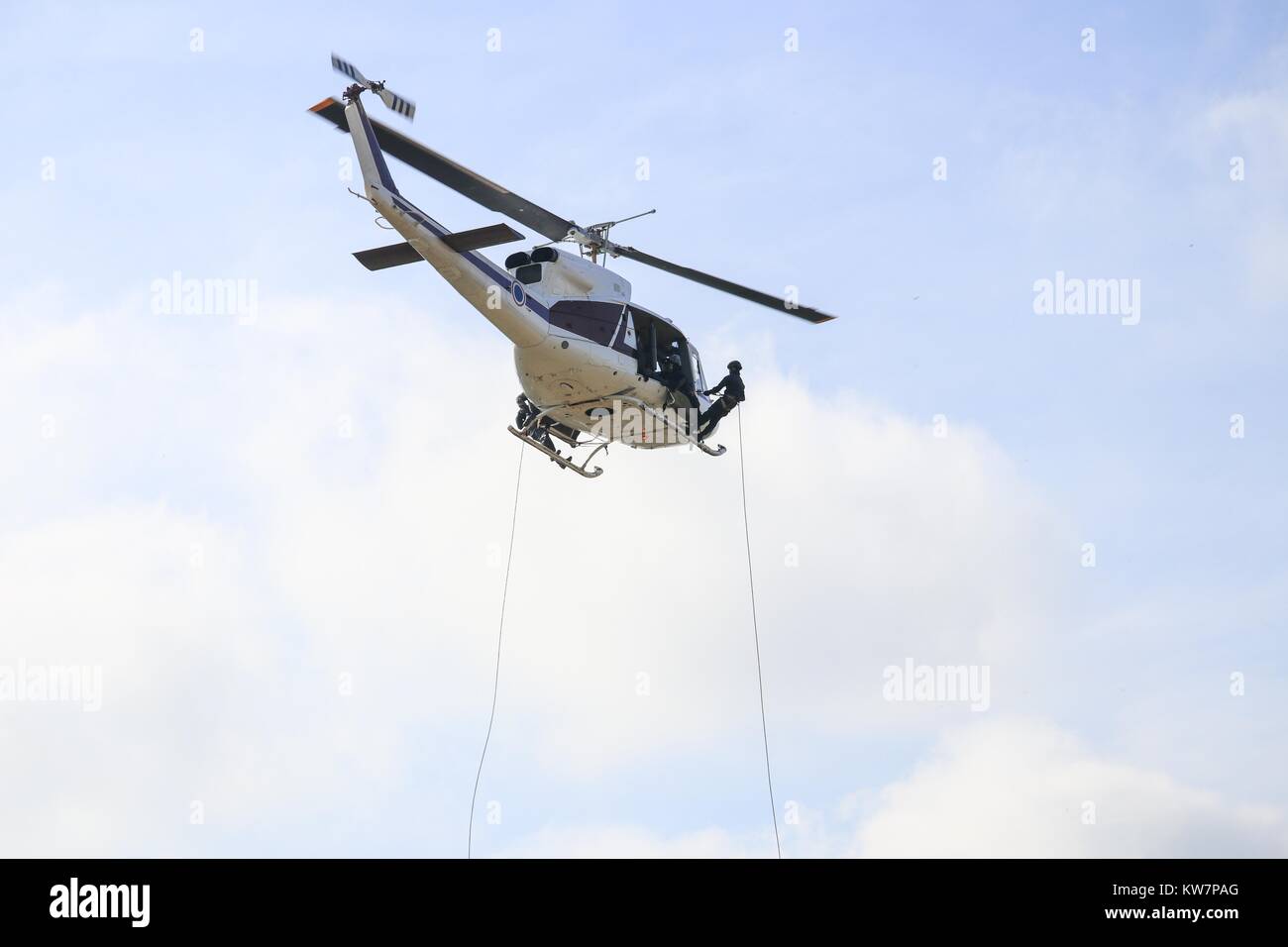 Soldier rappelling from helicopter in blue sky with blur propeller ...